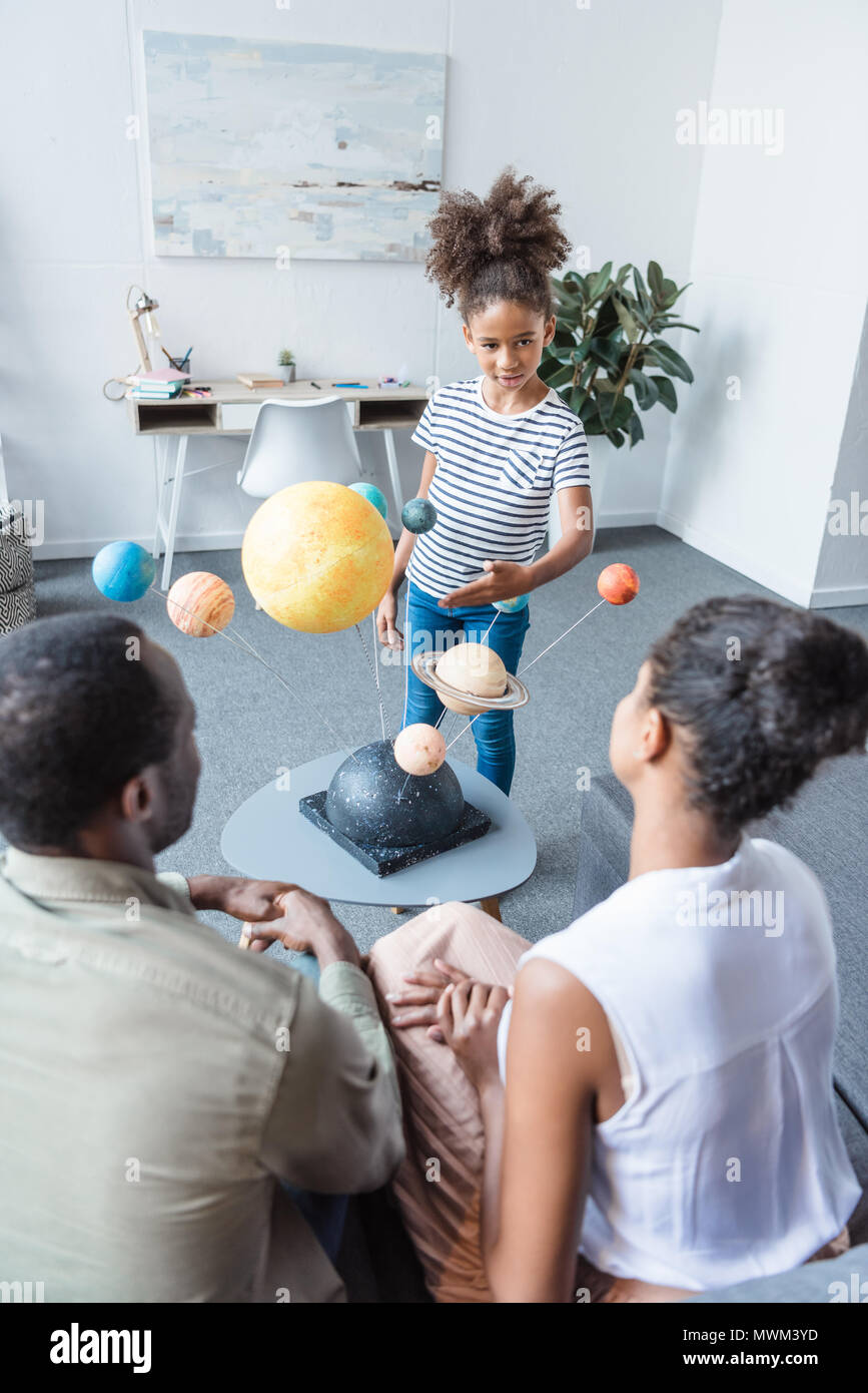 Little girl telling her parents about a big solar system model placed ...