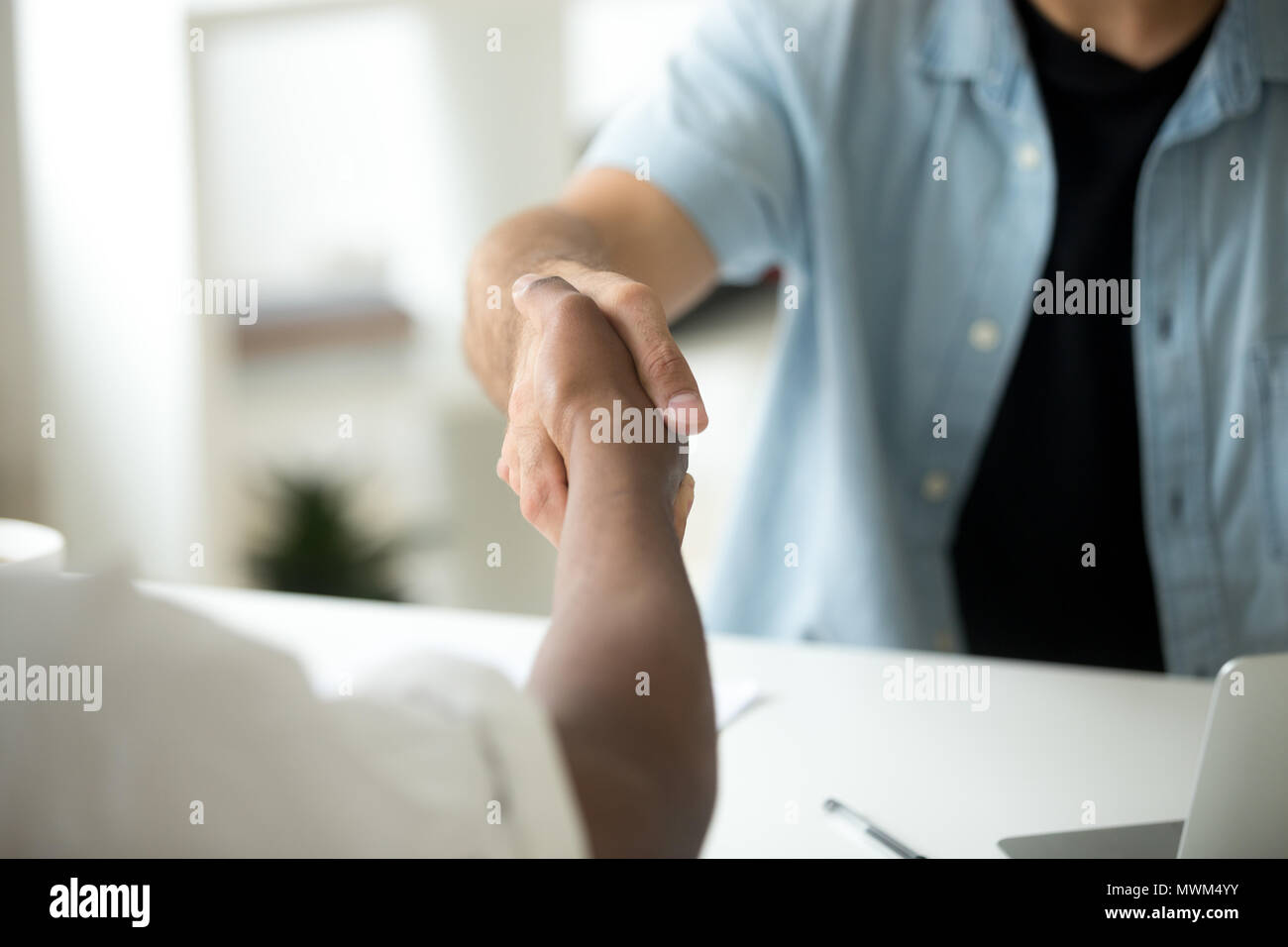 Close up of multiracial handshake over office desk Stock Photo - Alamy