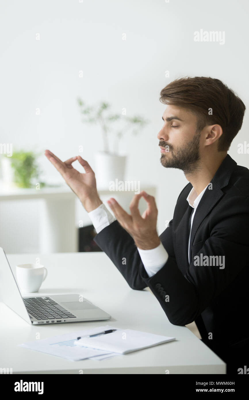 Calm businessman relaxing and meditating at workplace in office Stock ...