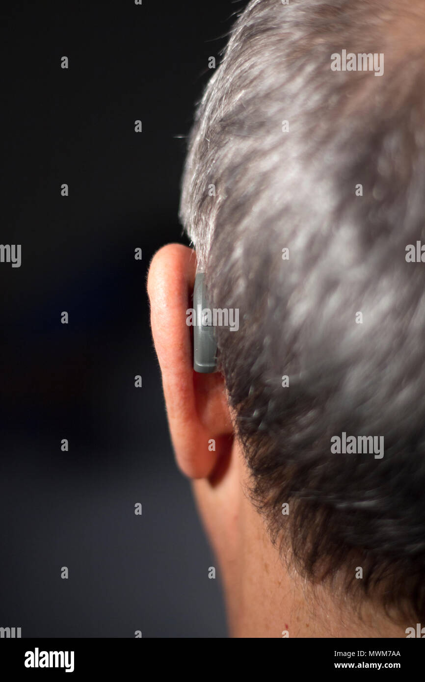Deaf senior citizen man wearing modern digital high technology hearing ...