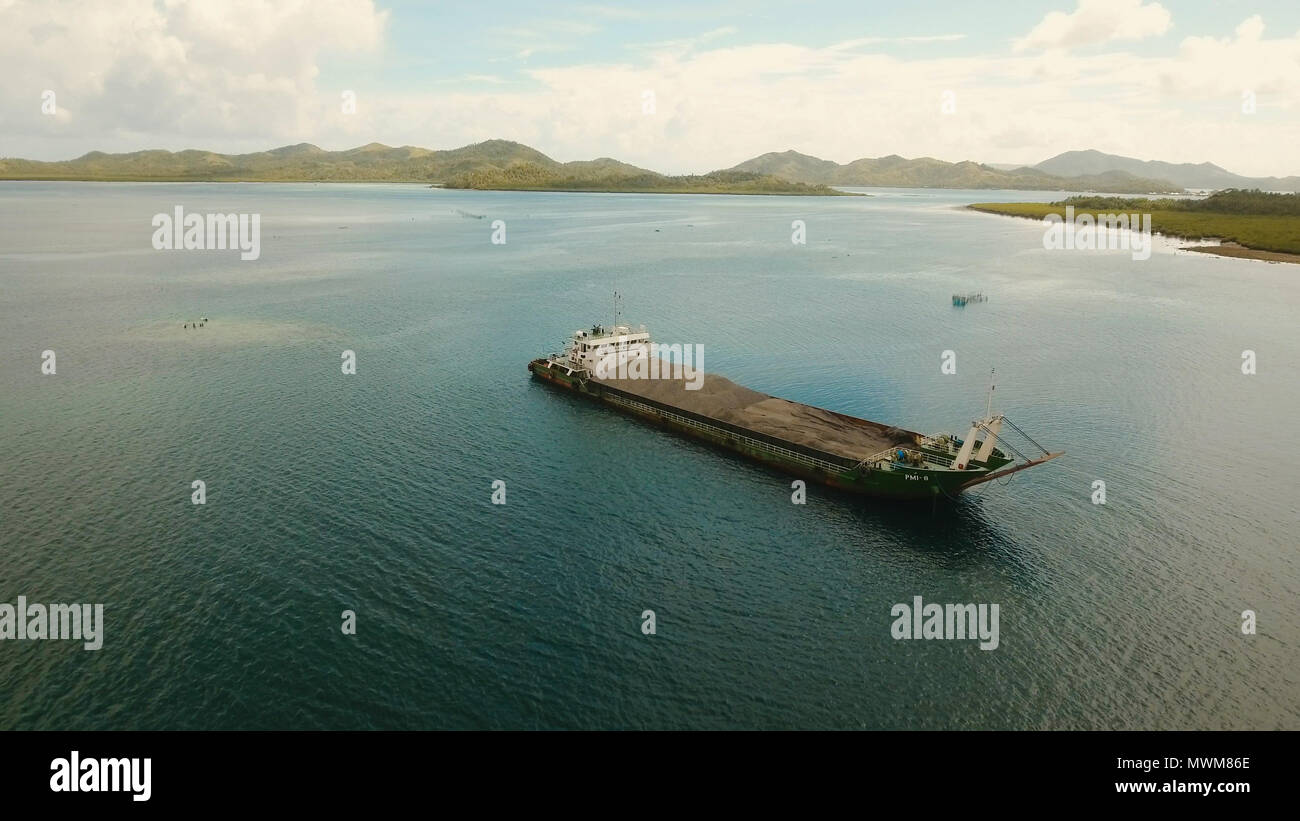 Cargo and passenger port with barges and cargo ships on tropical island ...