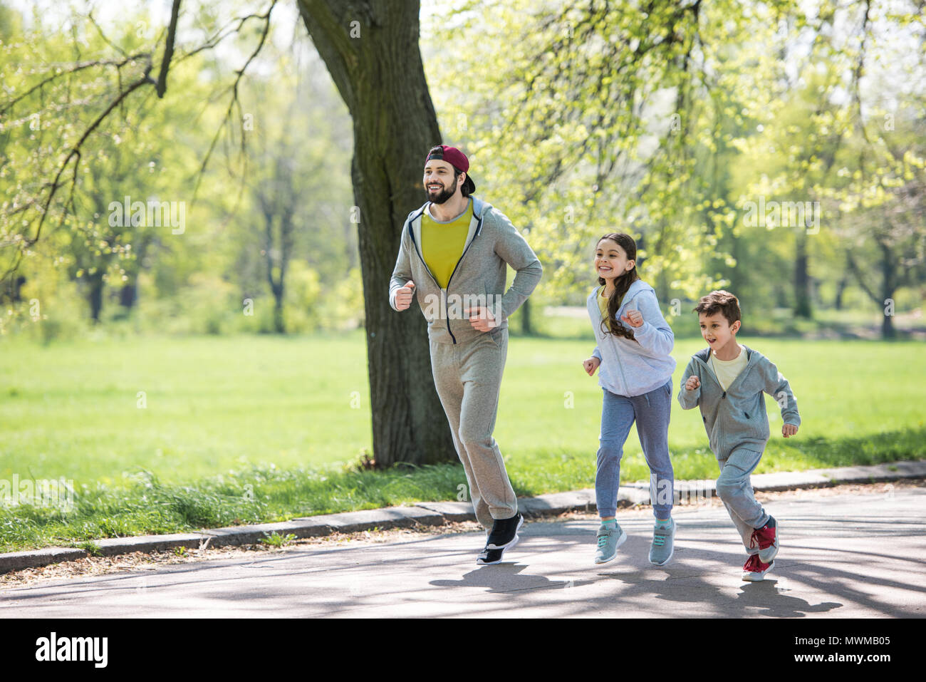 happy sportive family running on path in park Stock Photo - Alamy