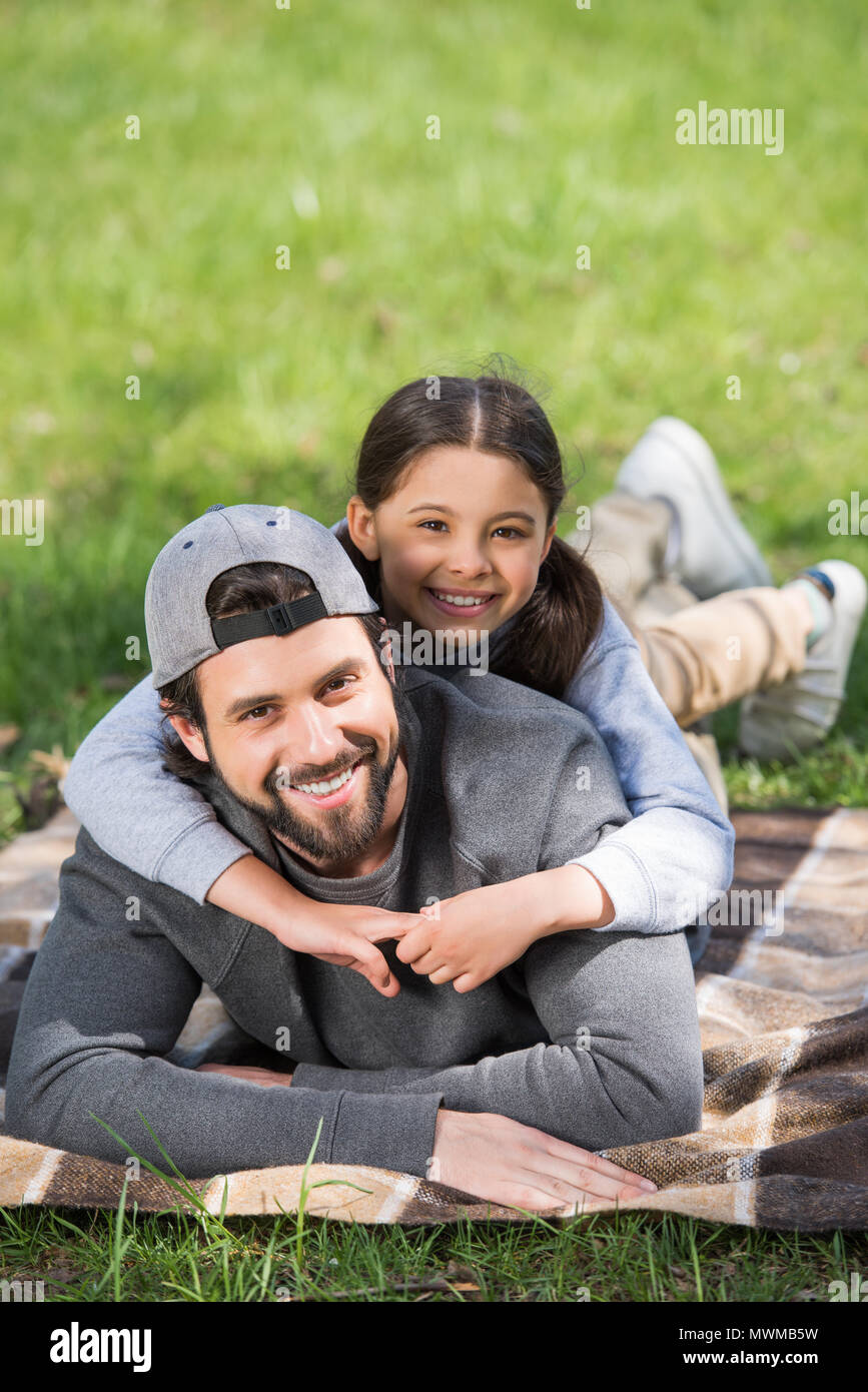 smiling daughter laying on father back in park Stock Photo - Alamy