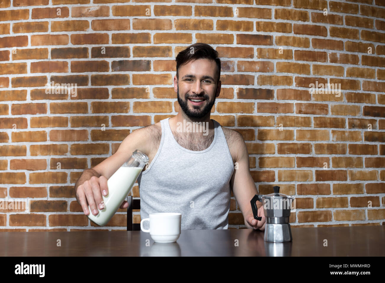 handsome young man pouring milk from bottle at breakfast Stock Photo ...