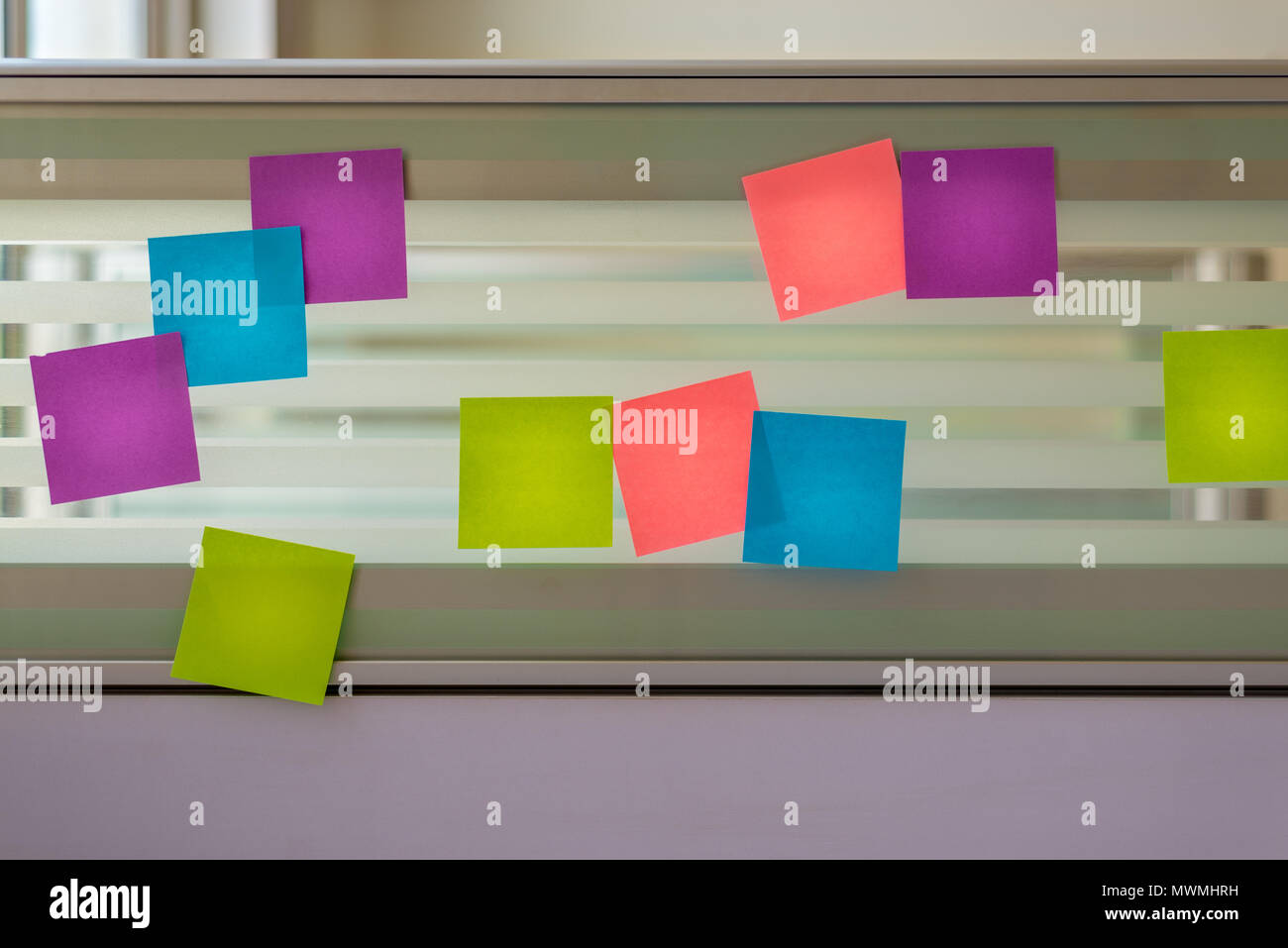 Randomly scattered colored sticky notes over glass screen of a bench ...