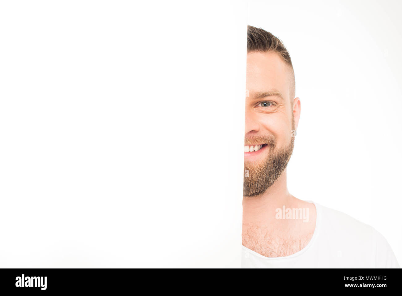 'Happy man standing behind and looking out of large blank white banner ...