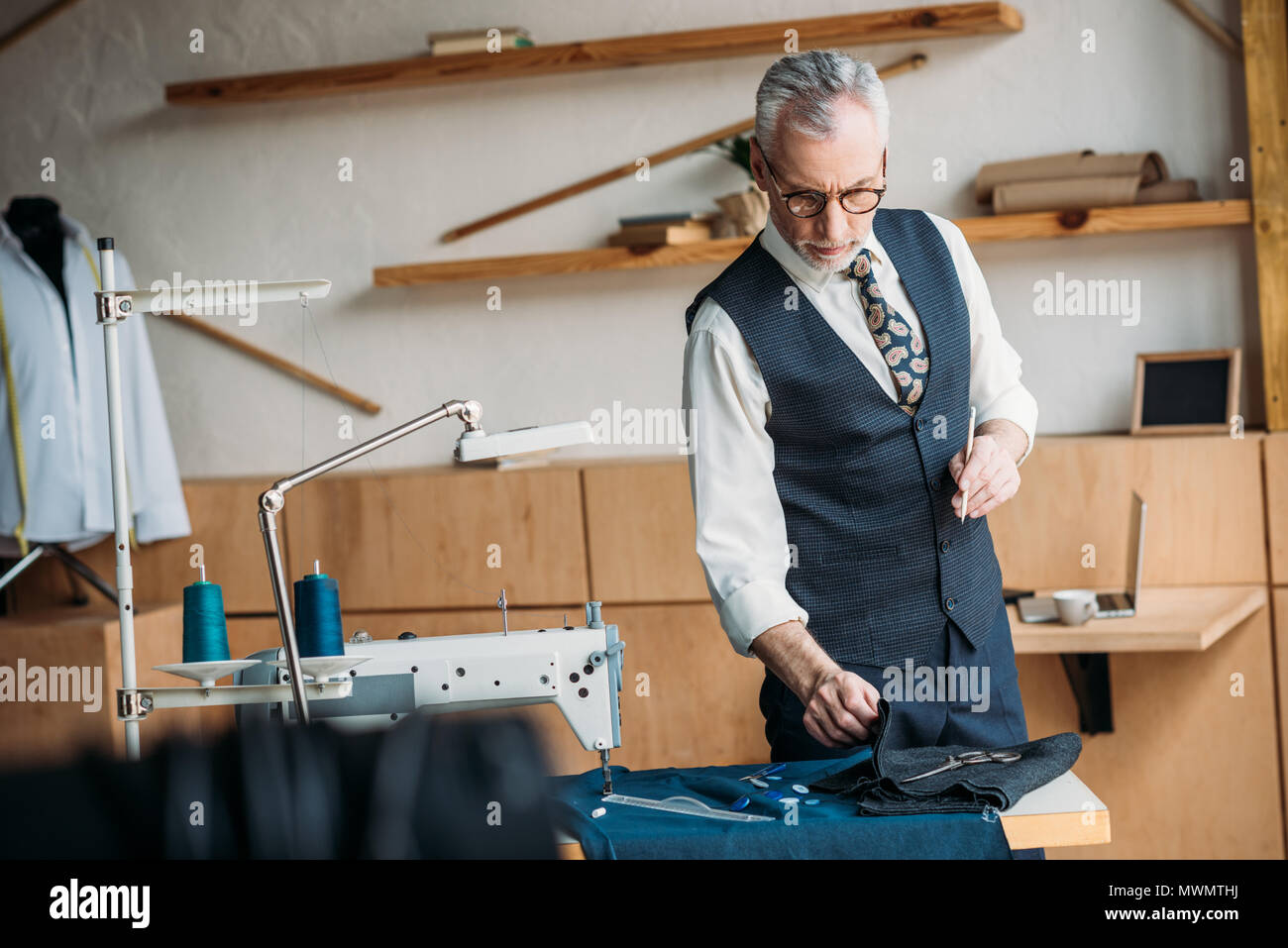 senior tailor examining cloth at sewing workshop Stock Photo - Alamy