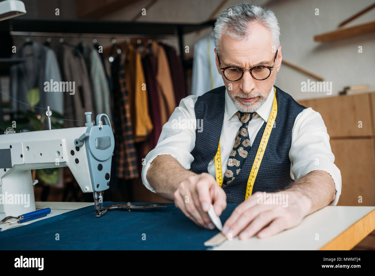senior tailor drawing outline on cloth at sewing workshop Stock Photo ...