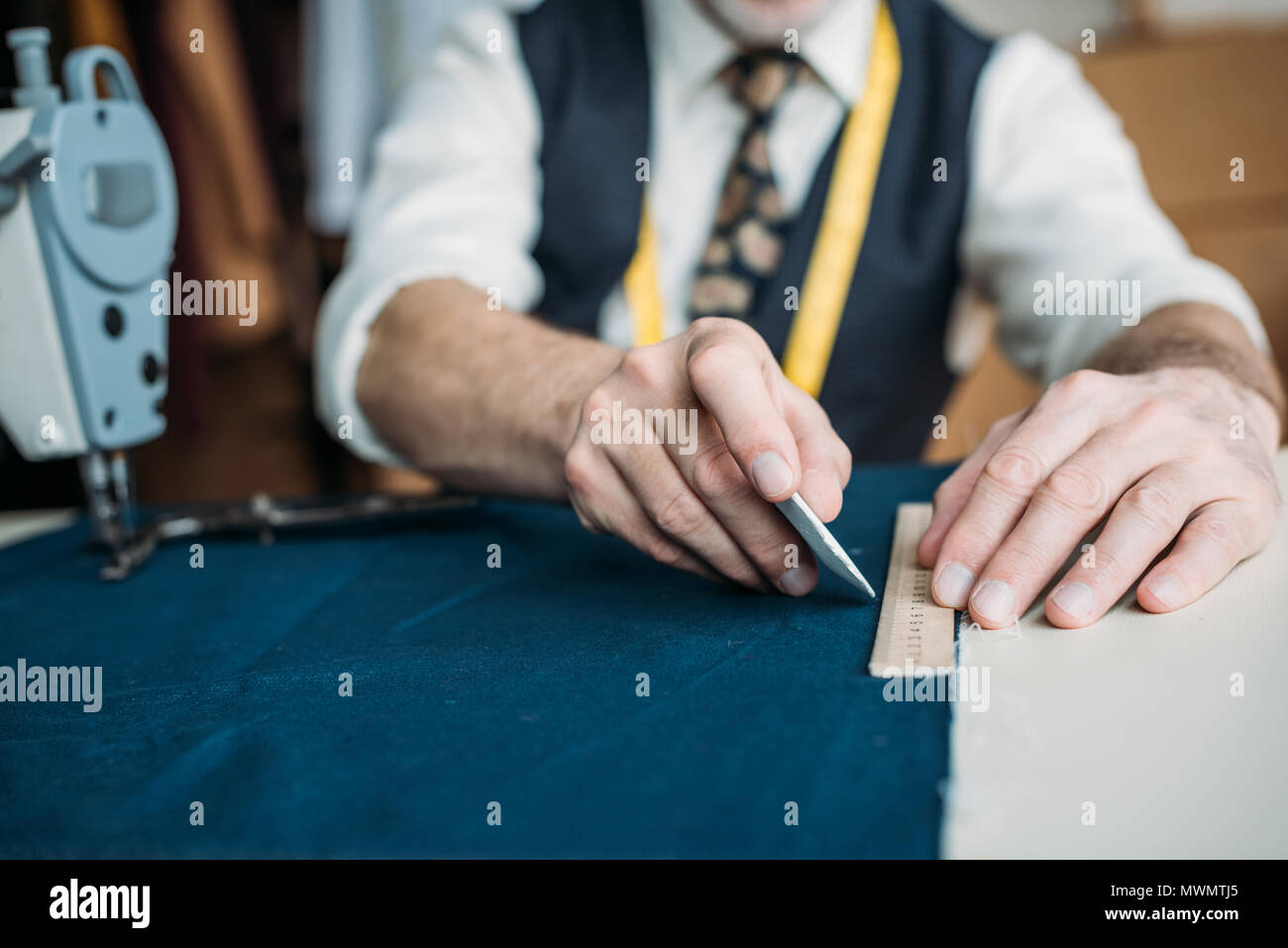cropped image of tailor drawing outline on cloth at sewing workshop ...