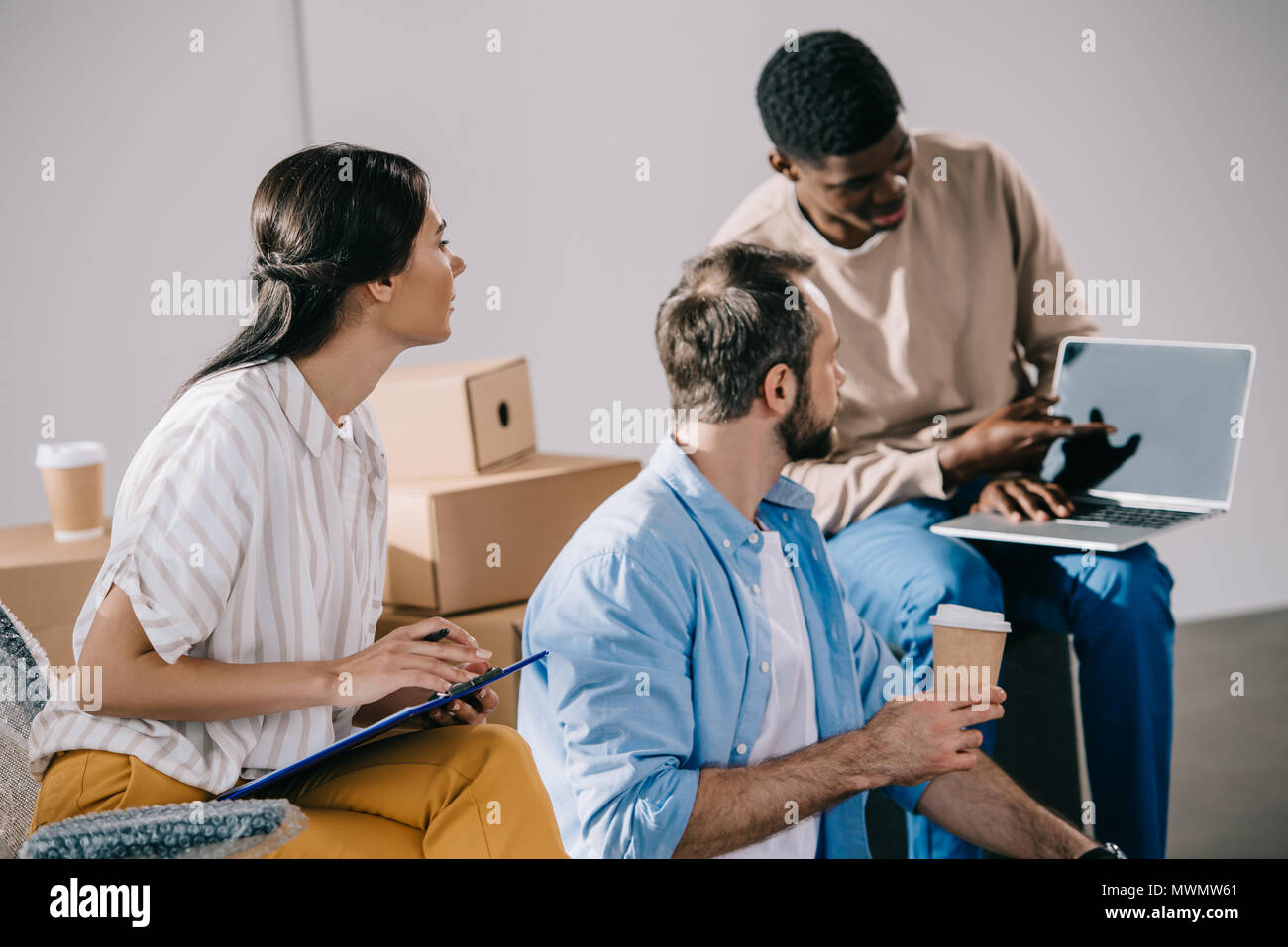 coworkers looking at african american businessman showing laptop with ...