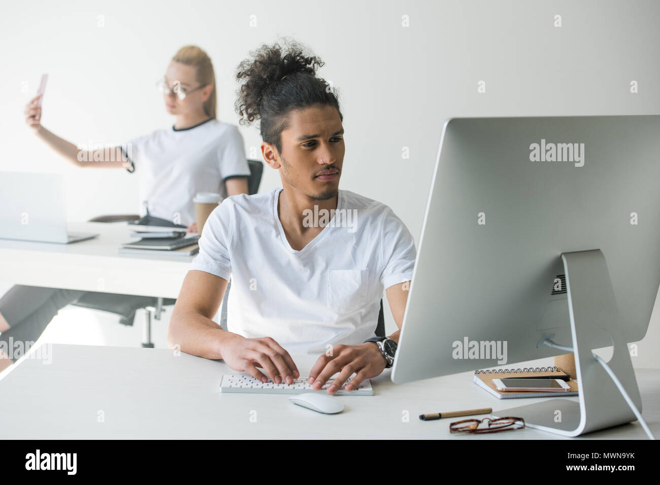 young african american man using desktop computer and female colleague ...
