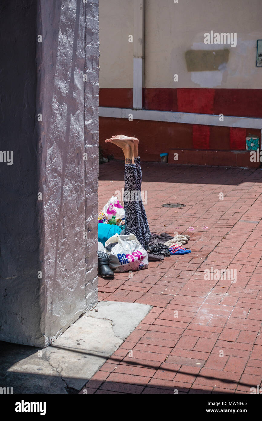 An older adult female homeless person lies on the city sidewalk and ...