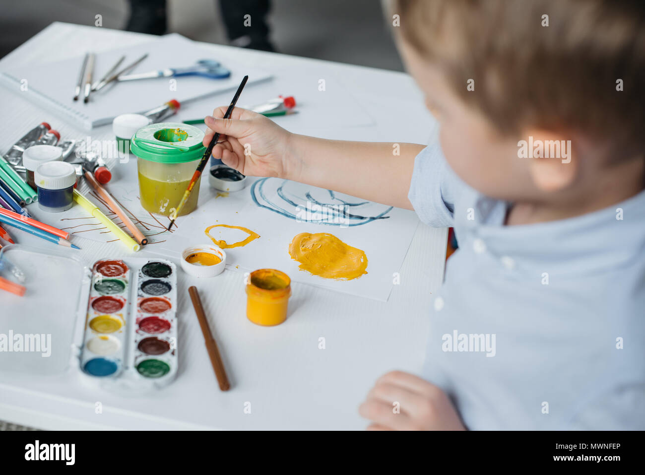 selective focus of little boy with brush and paintings drawing picture ...