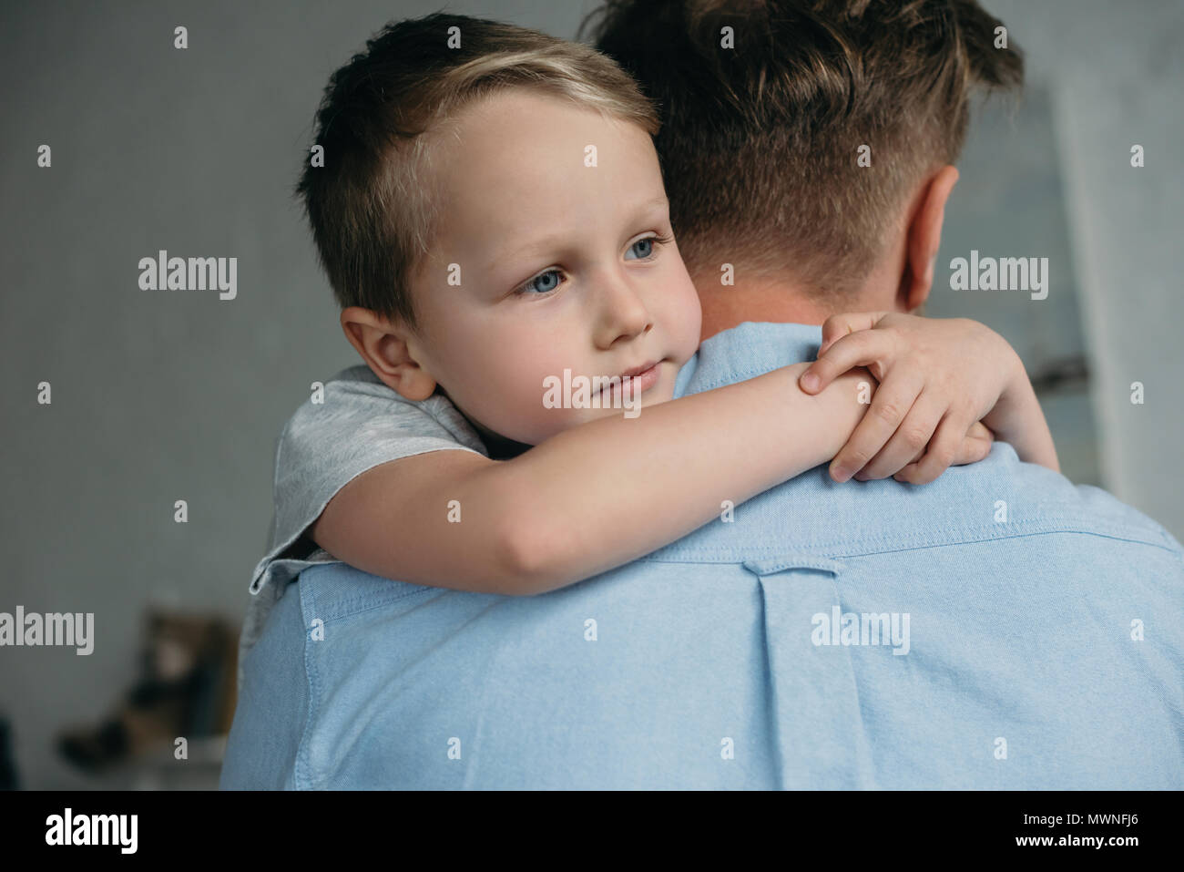 pensive little boy hugging father and looking away at home Stock Photo ...