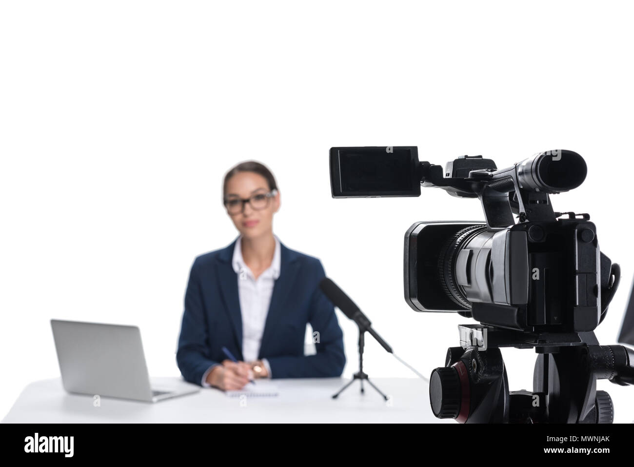 female newscaster sitting at table with laptop and microphone and ...