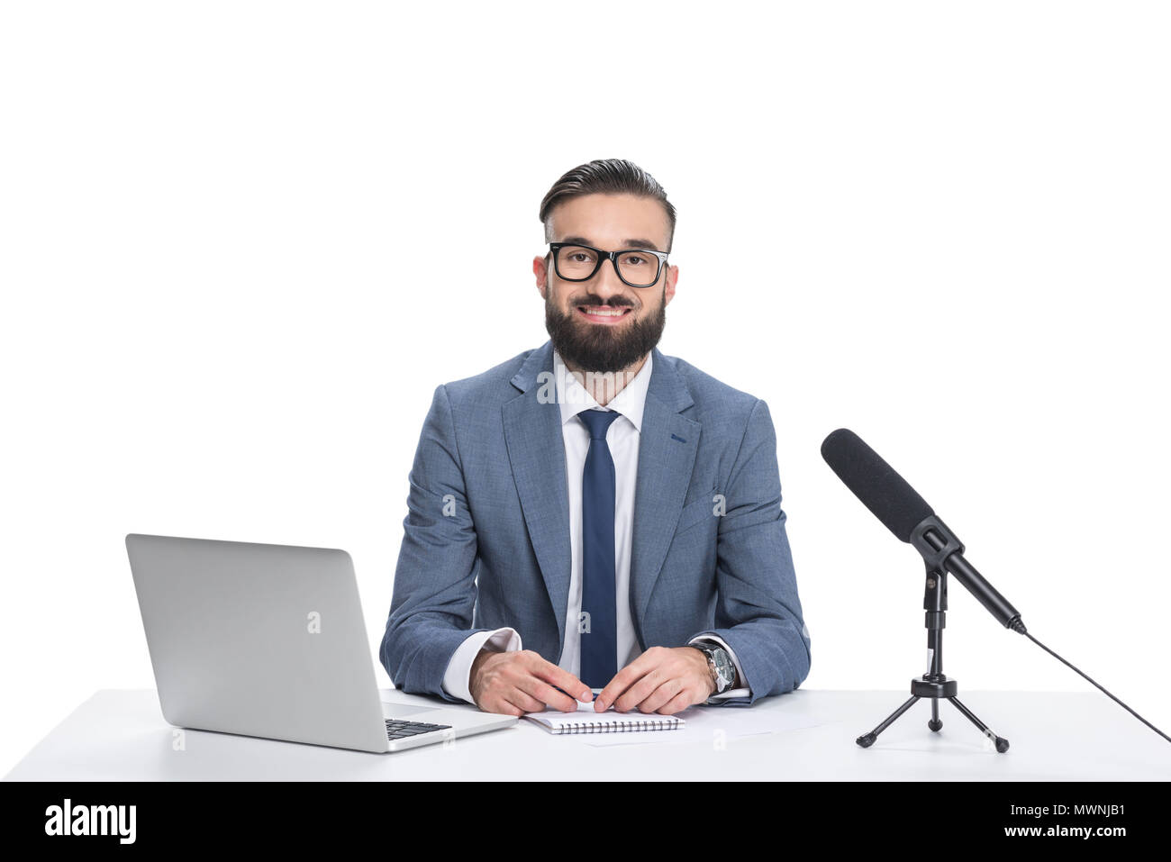 happy male newscaster sitting at table with laptop, notepad and ...