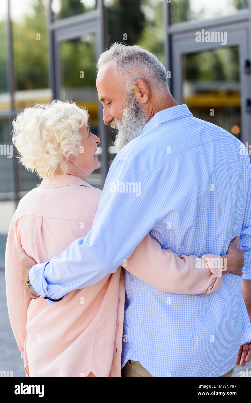 back view of smiling senior couple hugging each other on street Stock ...