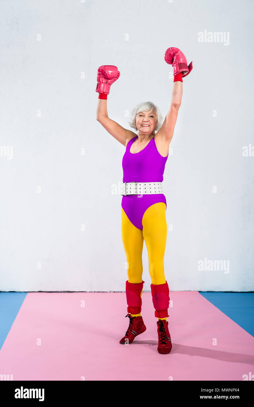 cheerful senior female boxer raising hands and smiling at camera Stock ...