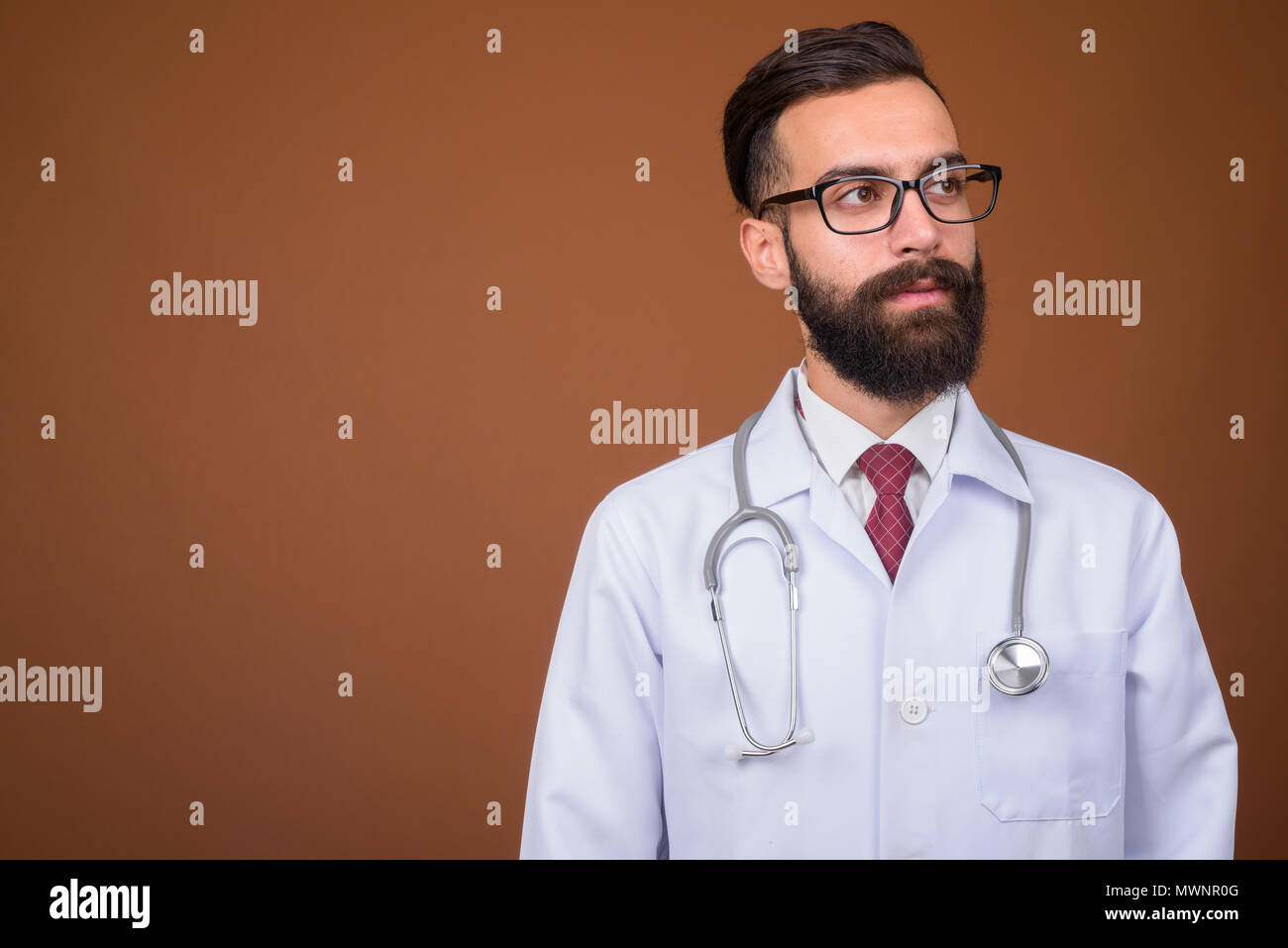 Young handsome bearded Persian man doctor against brown backgrou Stock ...