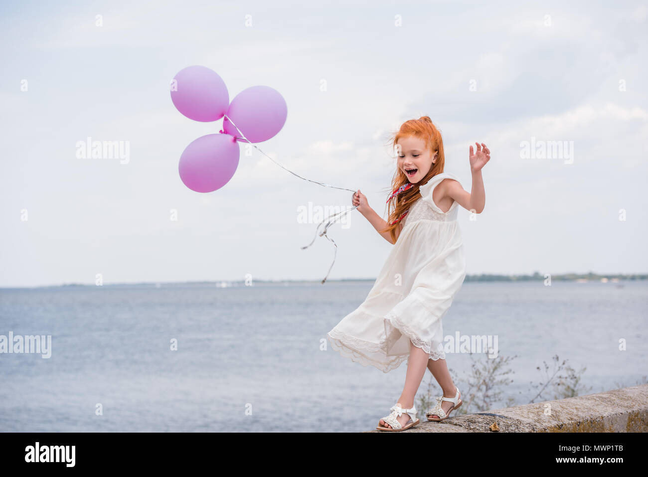 happy redhead girl holsing balloons and walking on quay Stock Photo - Alamy
