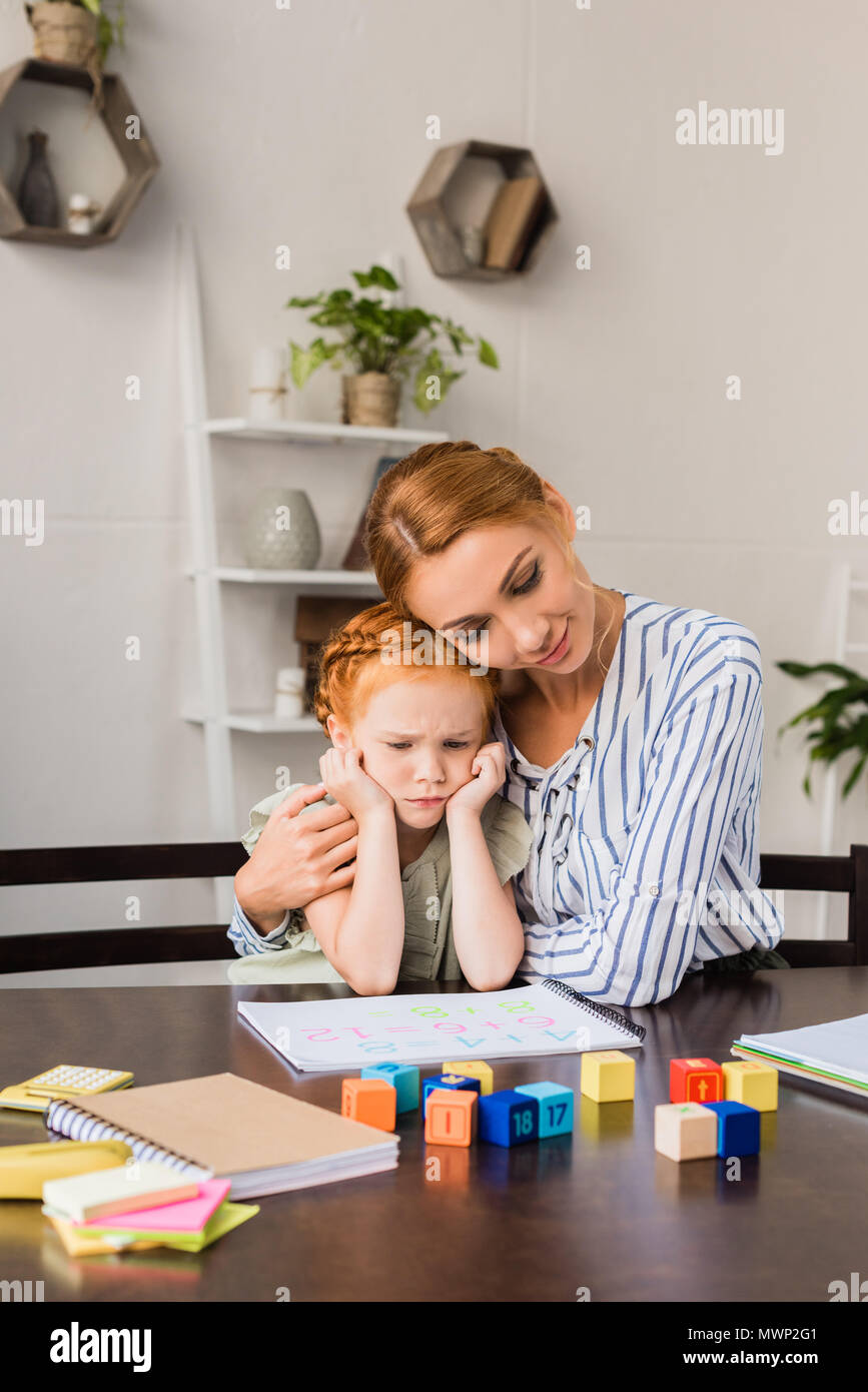 mother embracing daughter sad about math homework Stock Photo - Alamy