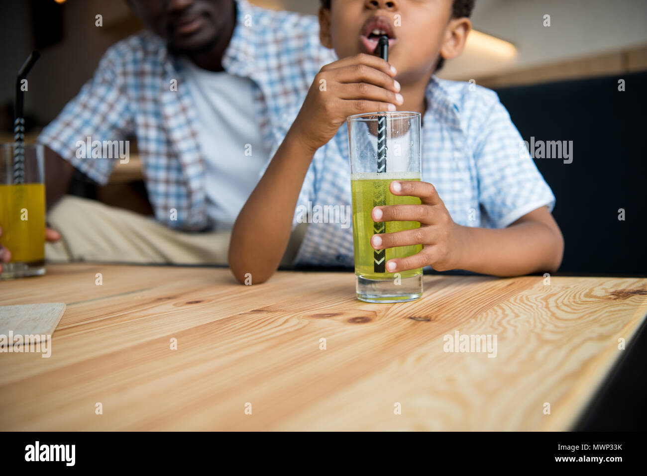 cropped shot of african american boy drinking lemonade while sitting ...