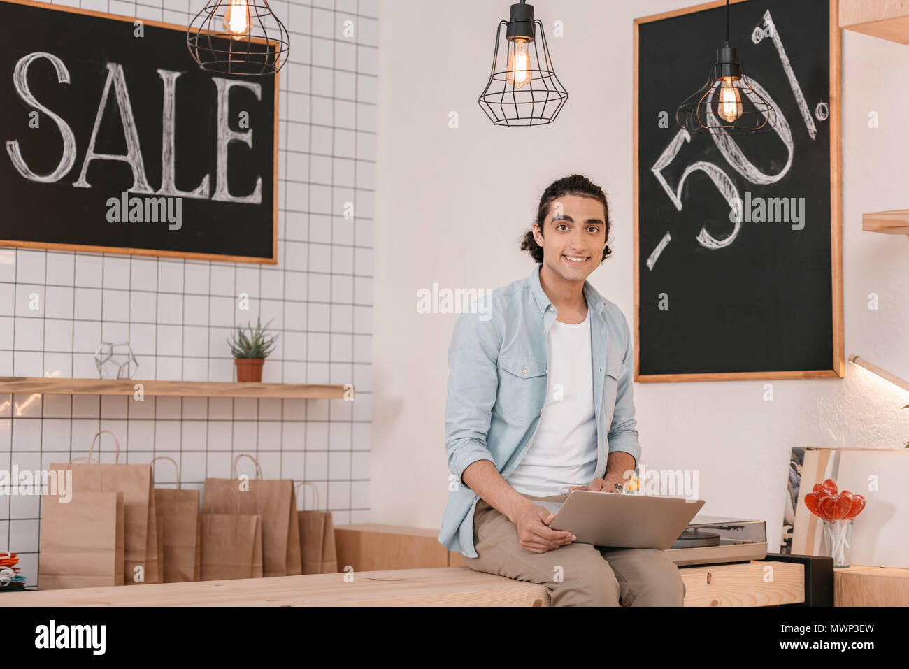 handsome smiling young man using laptop while sitting and working in ...