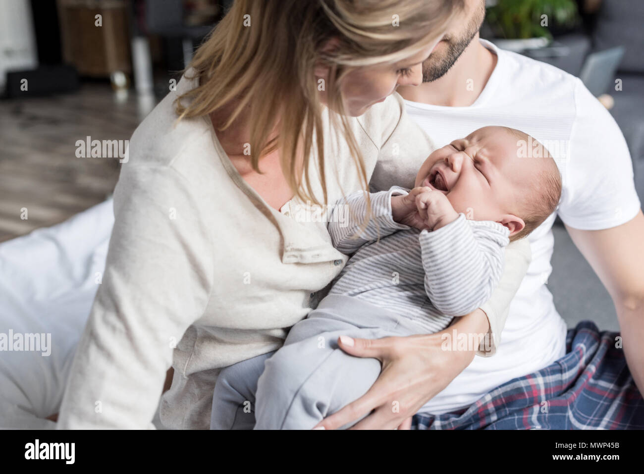 young parents holding ther little crying baby Stock Photo - Alamy