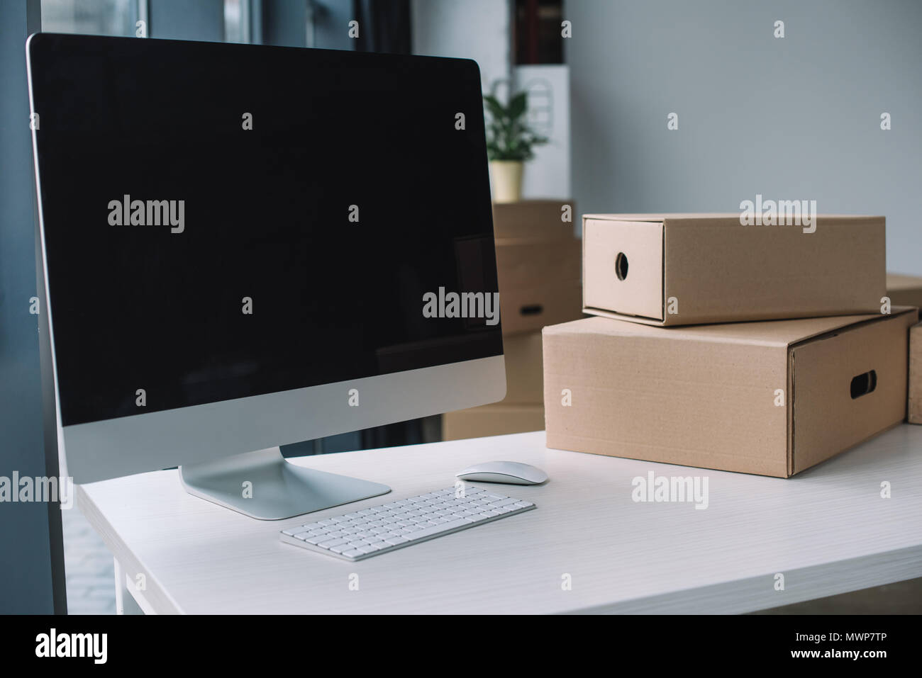 desktop computer with blank screen and cardboard boxes at workplace ...