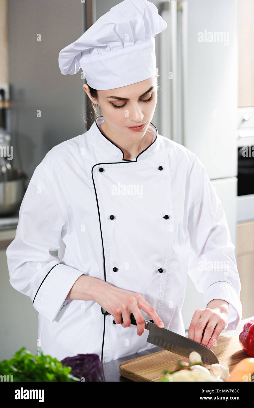 Professional female chef cutting ingredients by kitchen counter Stock ...