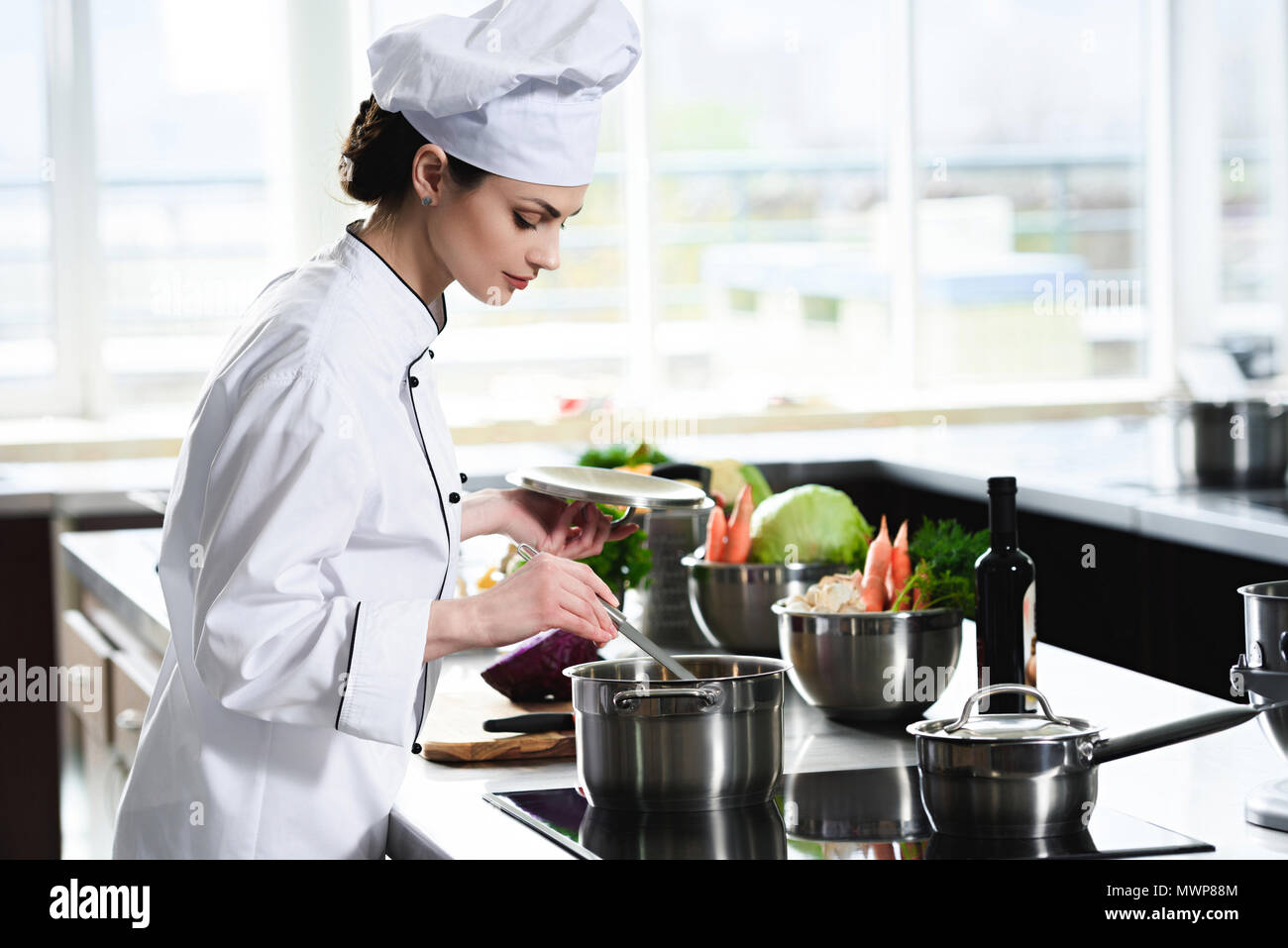 Woman chef cooking in pan on kitchen stove Stock Photo - Alamy