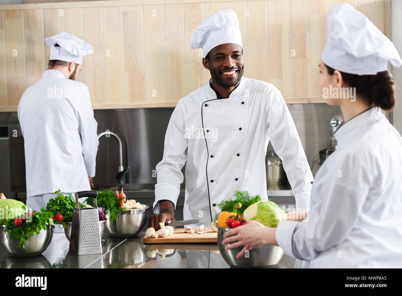 Multicultural cooks working together by kitchen counter Stock Photo - Alamy