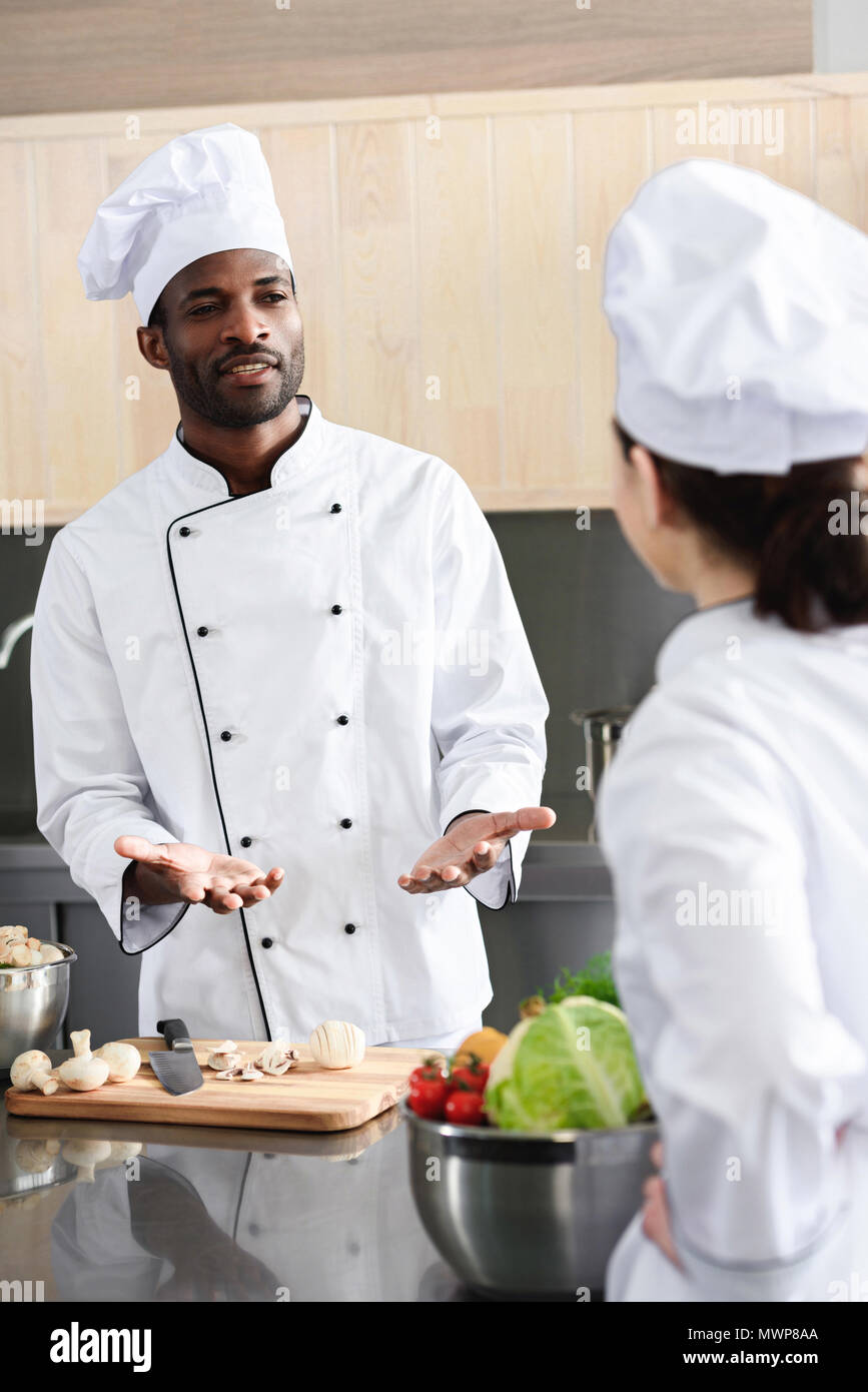 Multiracial chefs team discussing recipe and cooking on kitchen Stock ...