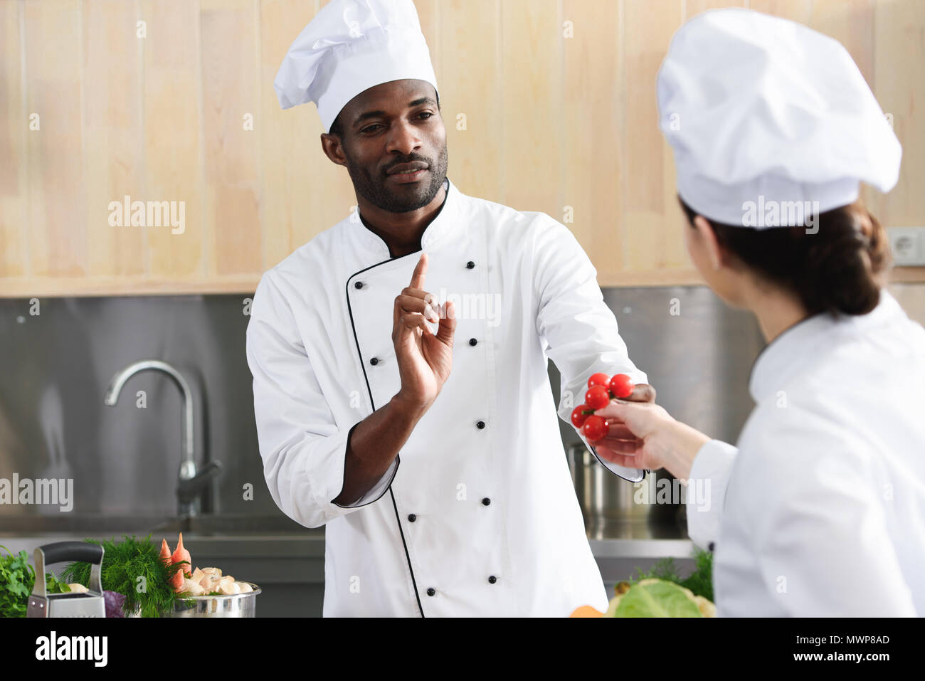 African american chef and female cook sharing cooking ingredients on ...