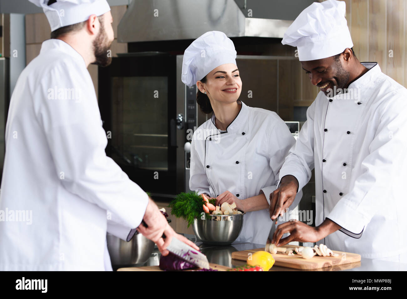 Multiracial team of cooks working together in restaurant kitchen Stock ...