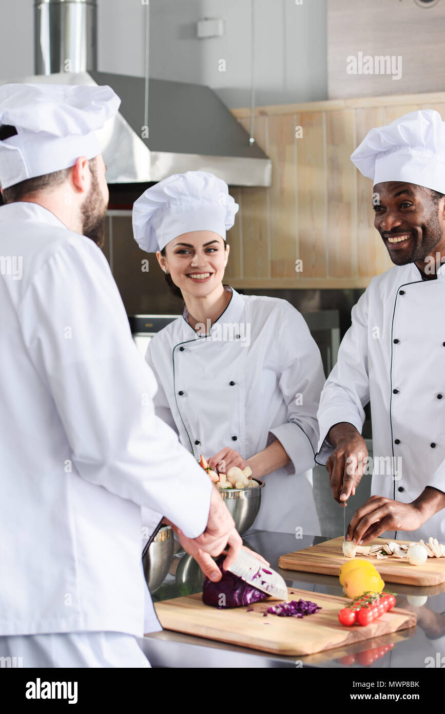 Multiracial chefs team smiling and cooking on modern kitchen Stock ...