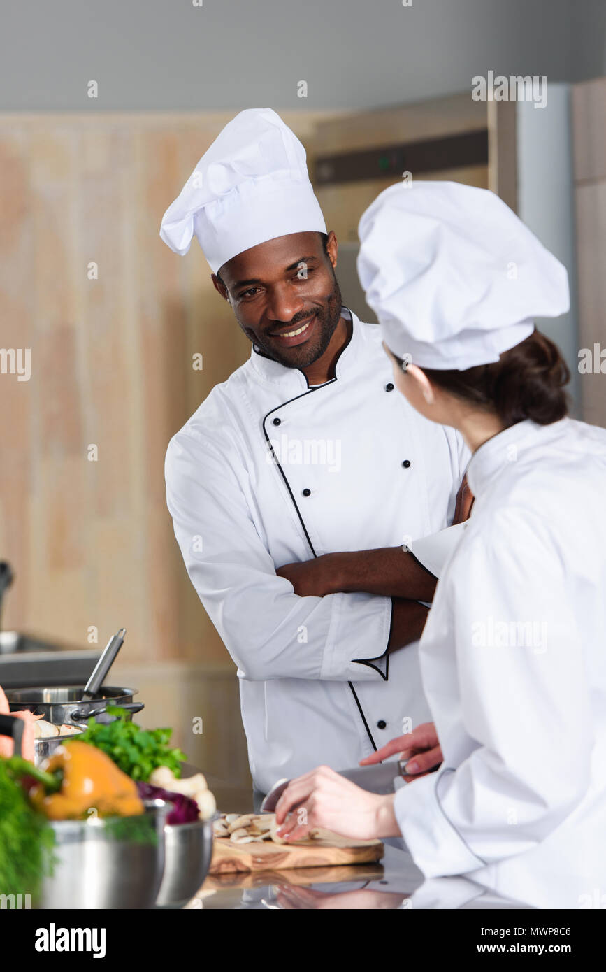 Multiracial team of cooks talking while cooking on modern kitchen Stock ...