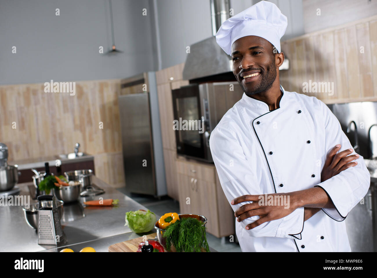 African american chef standing with arms folded by table with cooking ...