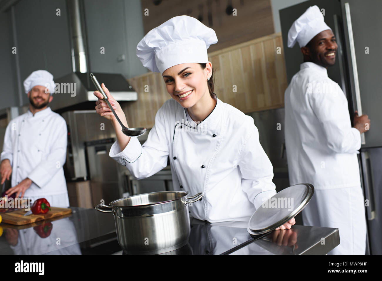 Female chef tasting dish by her multiracial team Stock Photo - Alamy