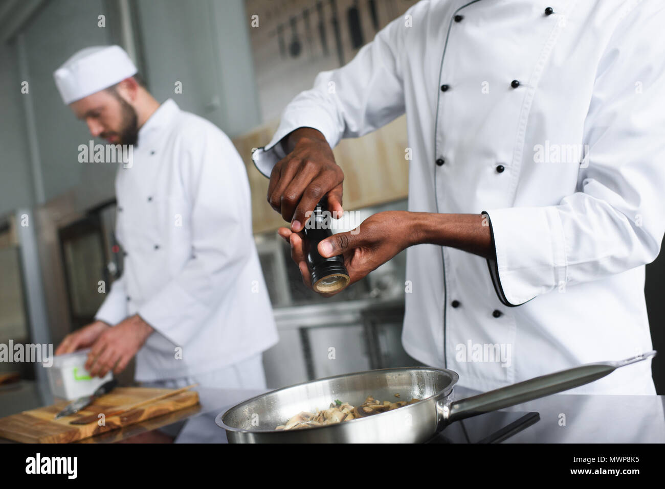 Multiracial chefs team cooking and seasoning hot dish Stock Photo - Alamy