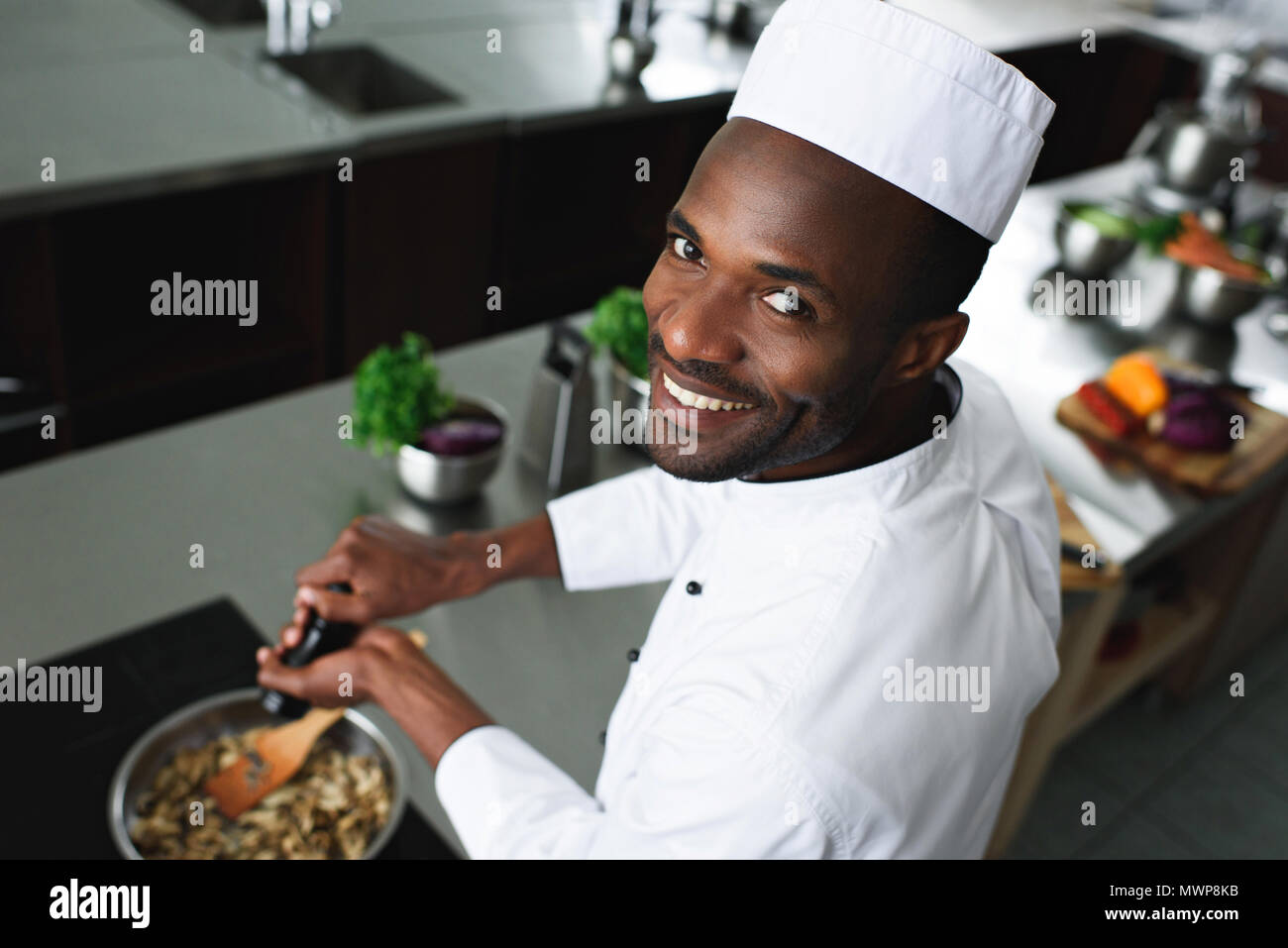Smiling African american cook seasoning dish by kitchen stove Stock ...