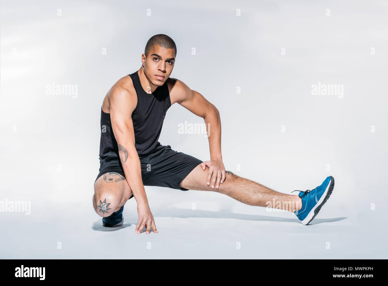 african american sportsman stretching legs and looking at camera Stock ...