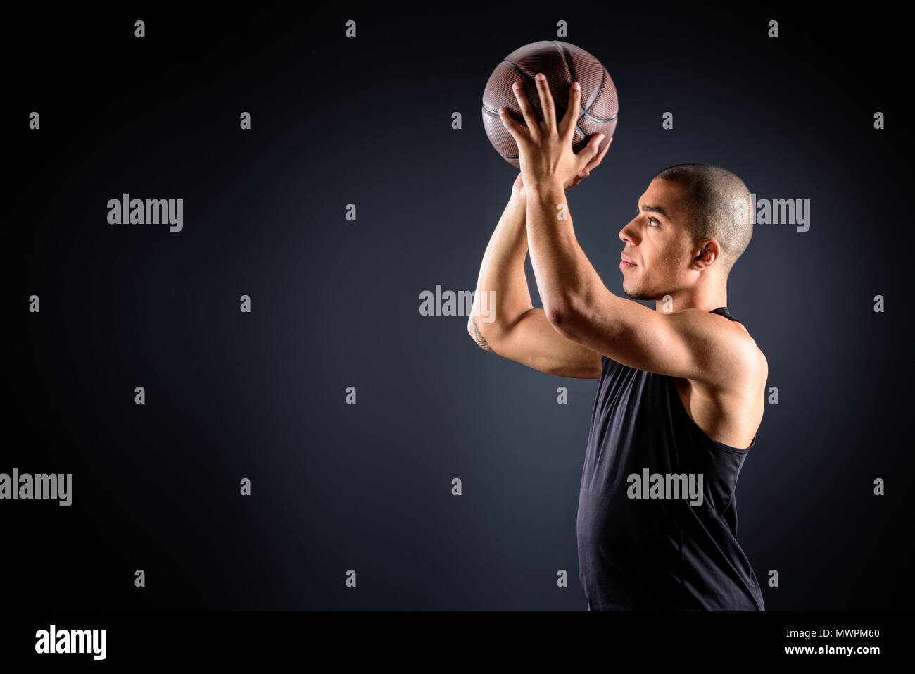 side view of african american basketball player throwing ball on black ...