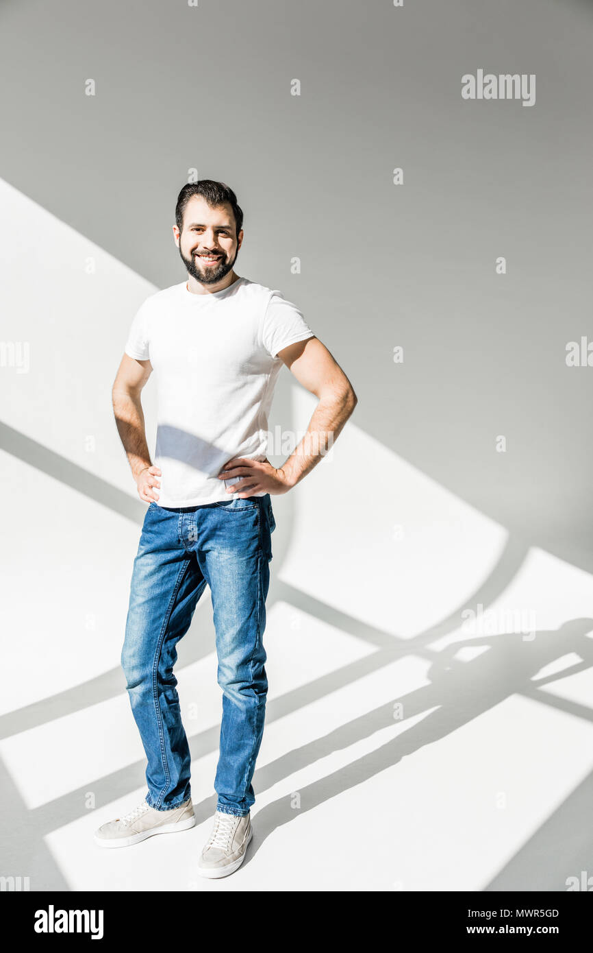full length view of handsome bearded man standing with hands on waist ...