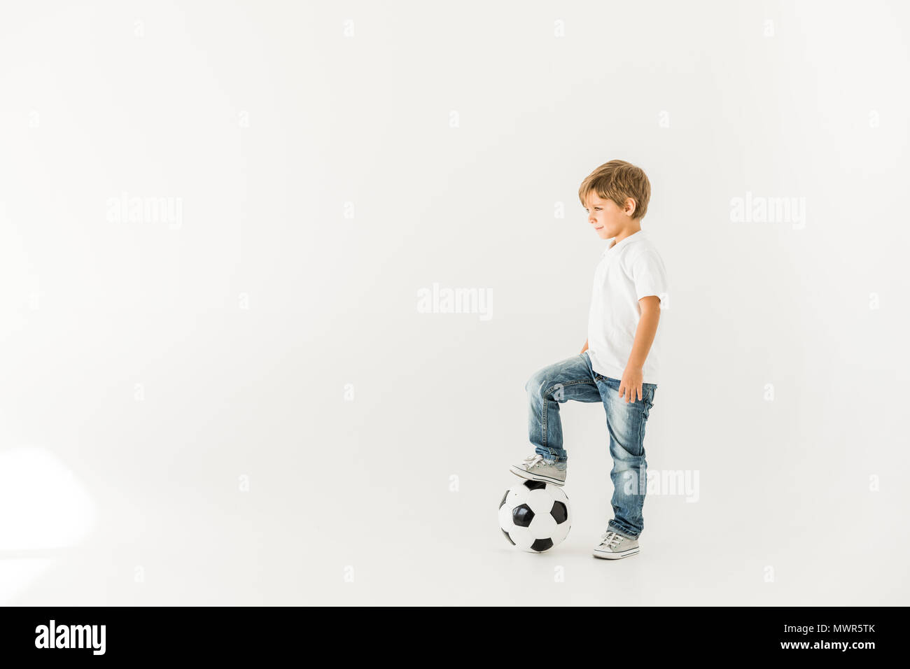side view of little boy playing with soccer ball isolated on white ...