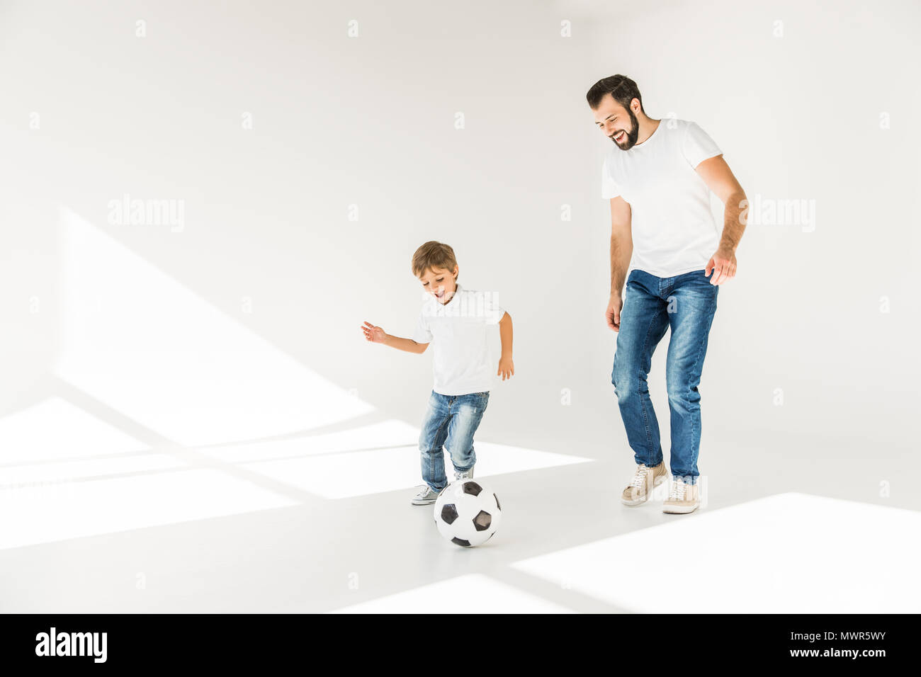 happy father and son playing with soccer ball on white Stock Photo - Alamy