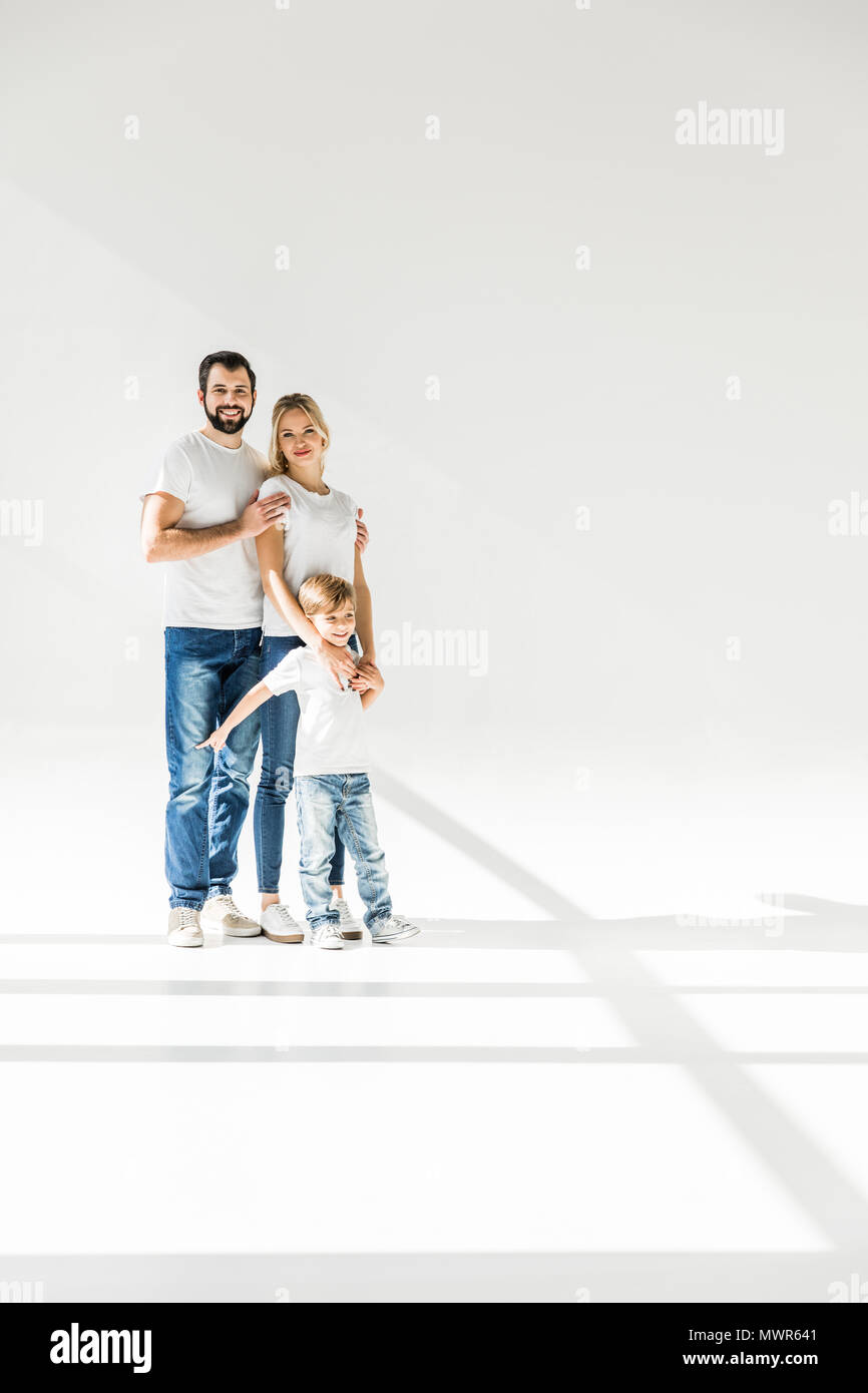 happy young family with one kid standing together and smiling at camera ...