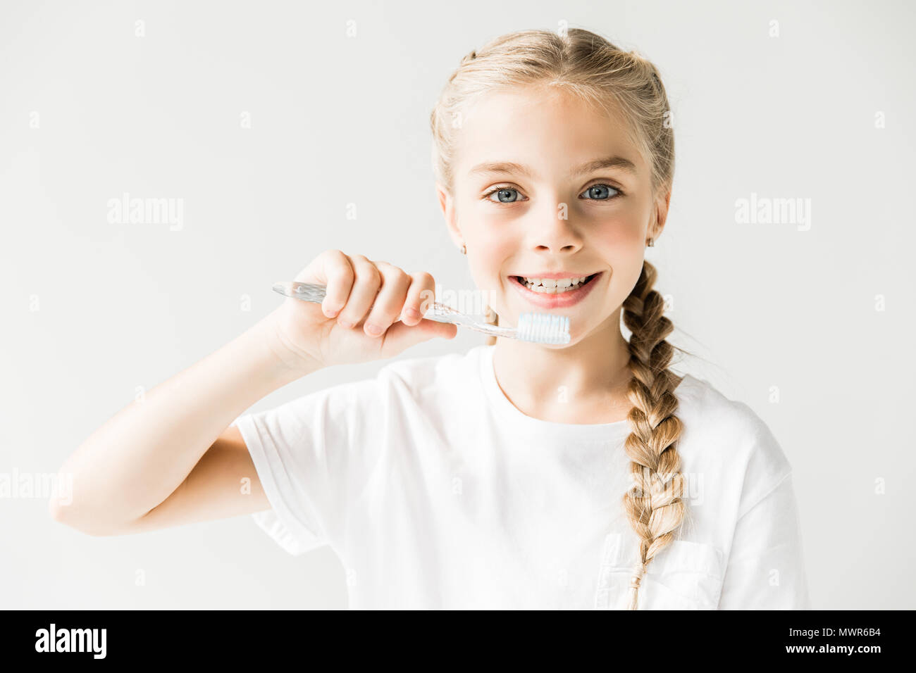 adorable happy child brushing teeth and smiling at camera isolated on ...