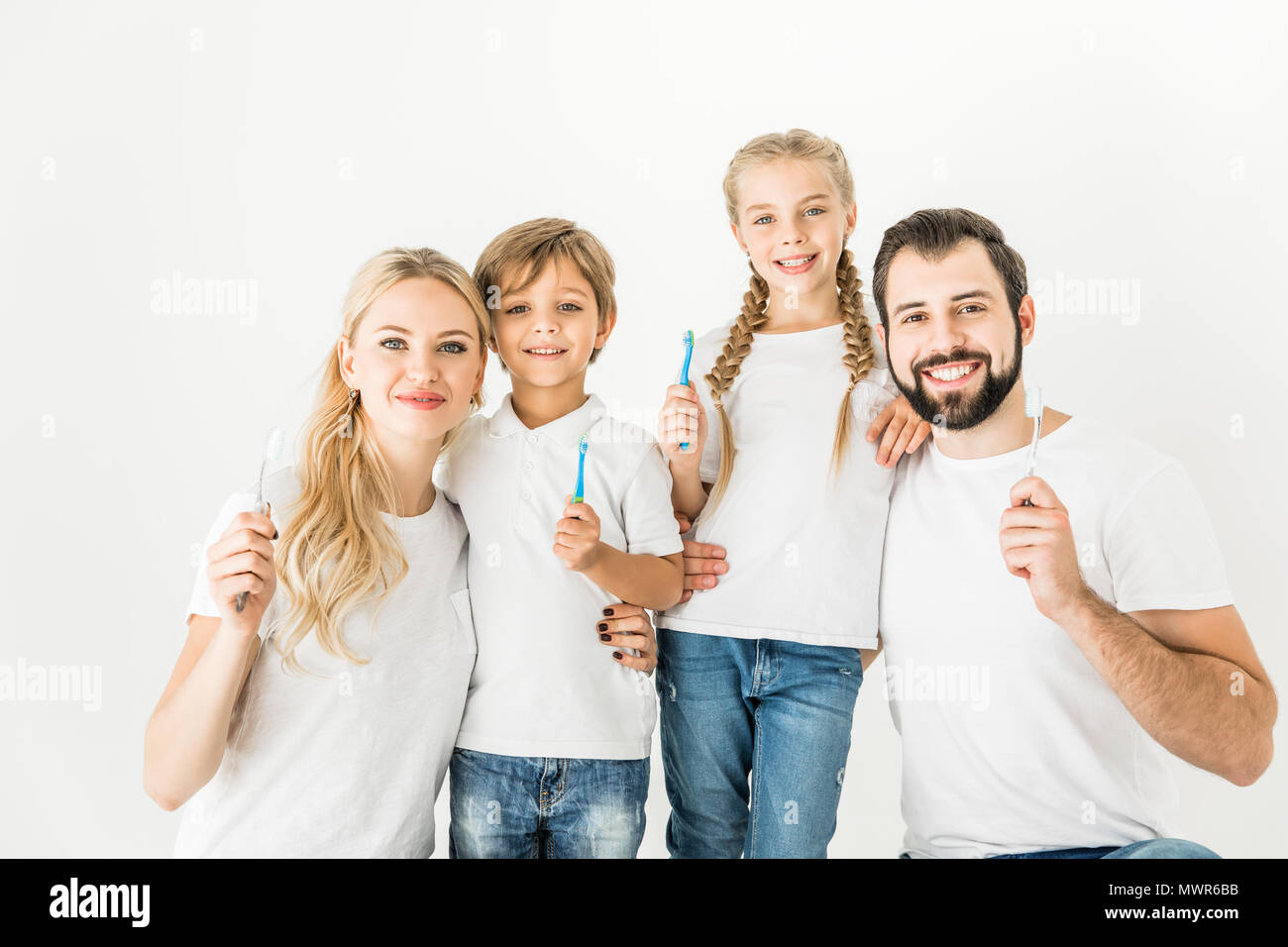 happy family holding toothbrushes and smiling at camera isolated on ...