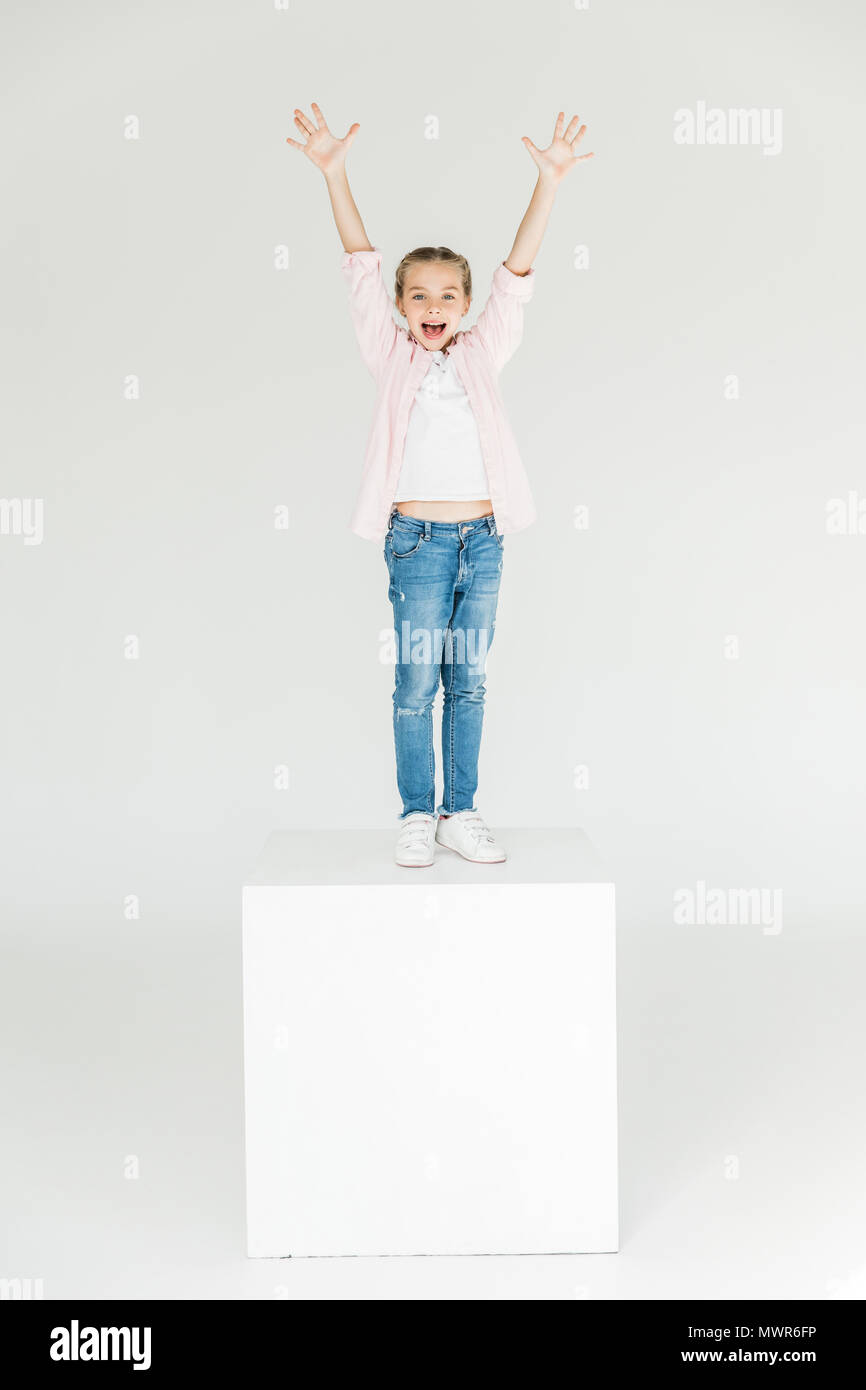 adorable little girl raising hands and smiling at camera isolated on ...